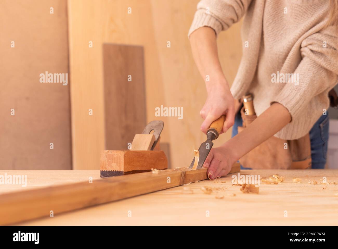 Top view of body part of anonymous carpenter carving wood on plank with ...