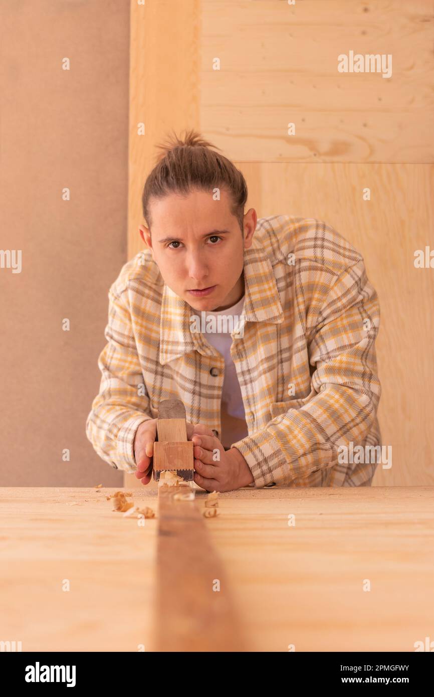 Happy male woodworker looking at camera and smiling while smoothing ...