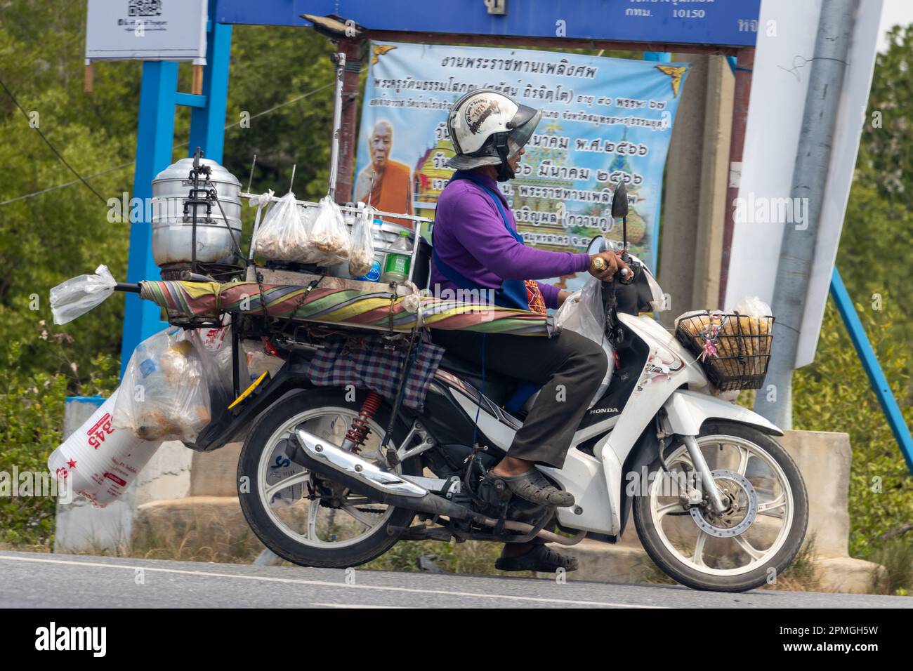 BANGKOK, THAILAND, MAR 24 2023, A man drives a motorcycle with a mobile ...