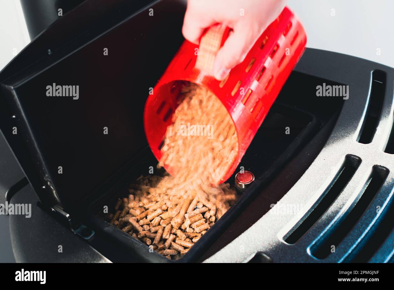 Close-up on pellets, black domestic pellet stove, man loading by hand ...