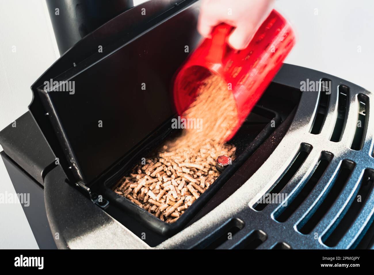 Close-up on pellets, black domestic pellet stove, man loading by hand ...