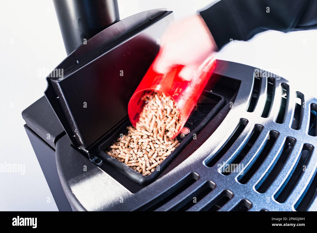 Close-up on pellets, black domestic pellet stove, man loading by hand ...