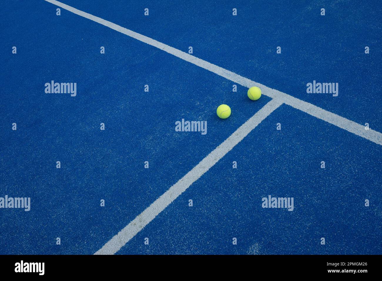 two balls next to the side of a blue paddle tennis court, racket sports ...