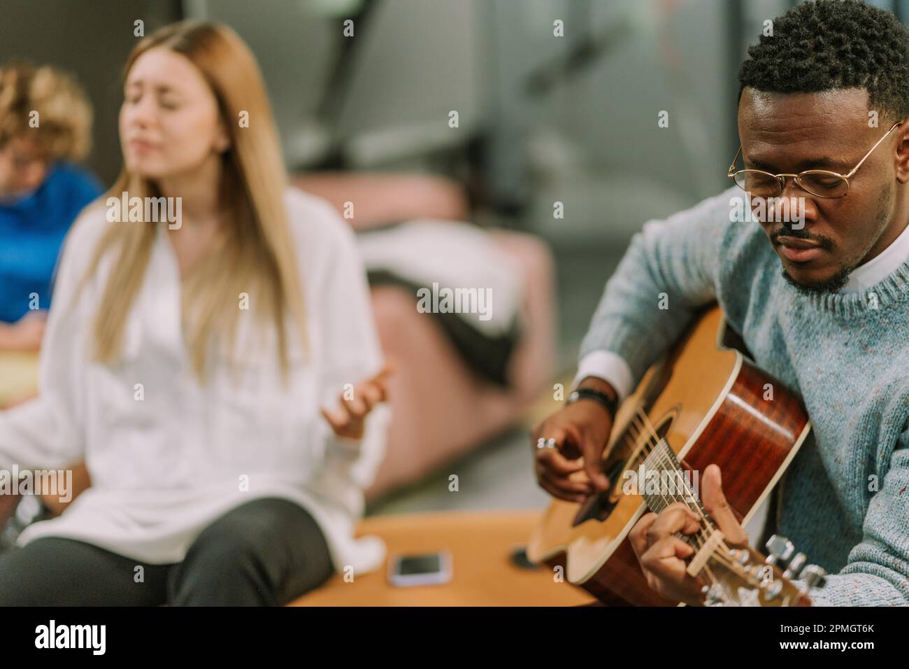 A photo of good looking black male person playing guitar. His female ...