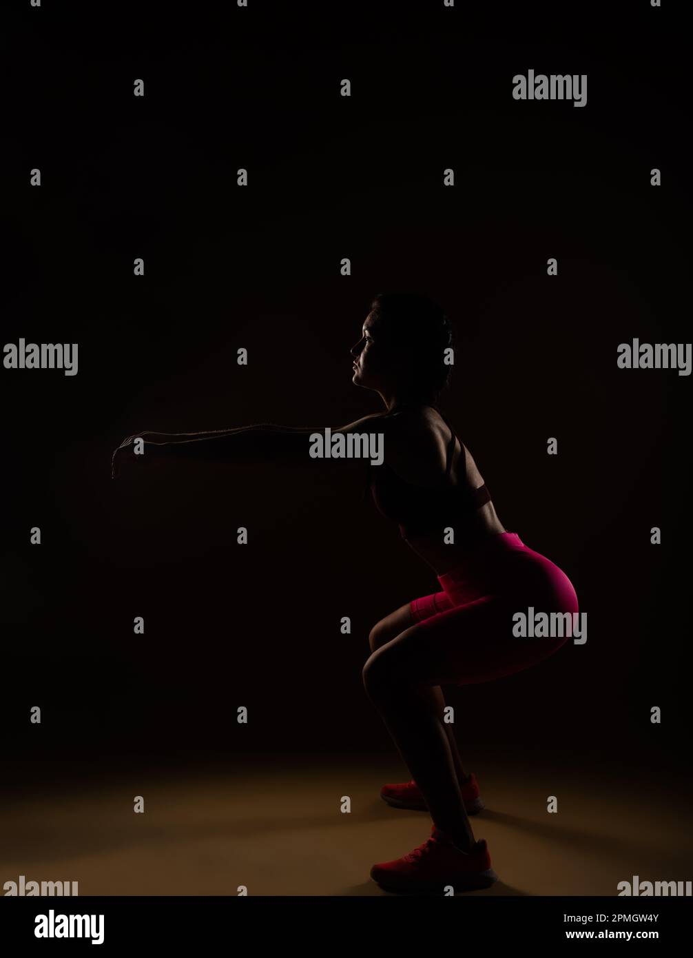 A side view photo of sporty woman doing squats with straighten arms ...
