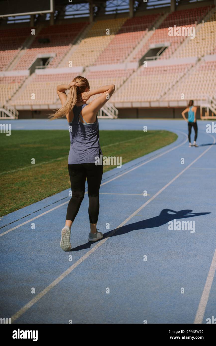 Two girls walking on a sports track at the stadium Stock Photo - Alamy