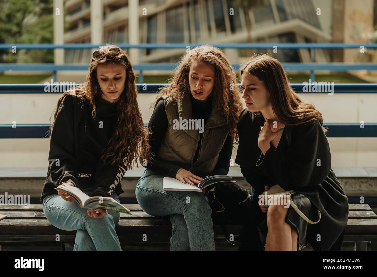 Two girls looking at their friend book. She is explaining them the ...