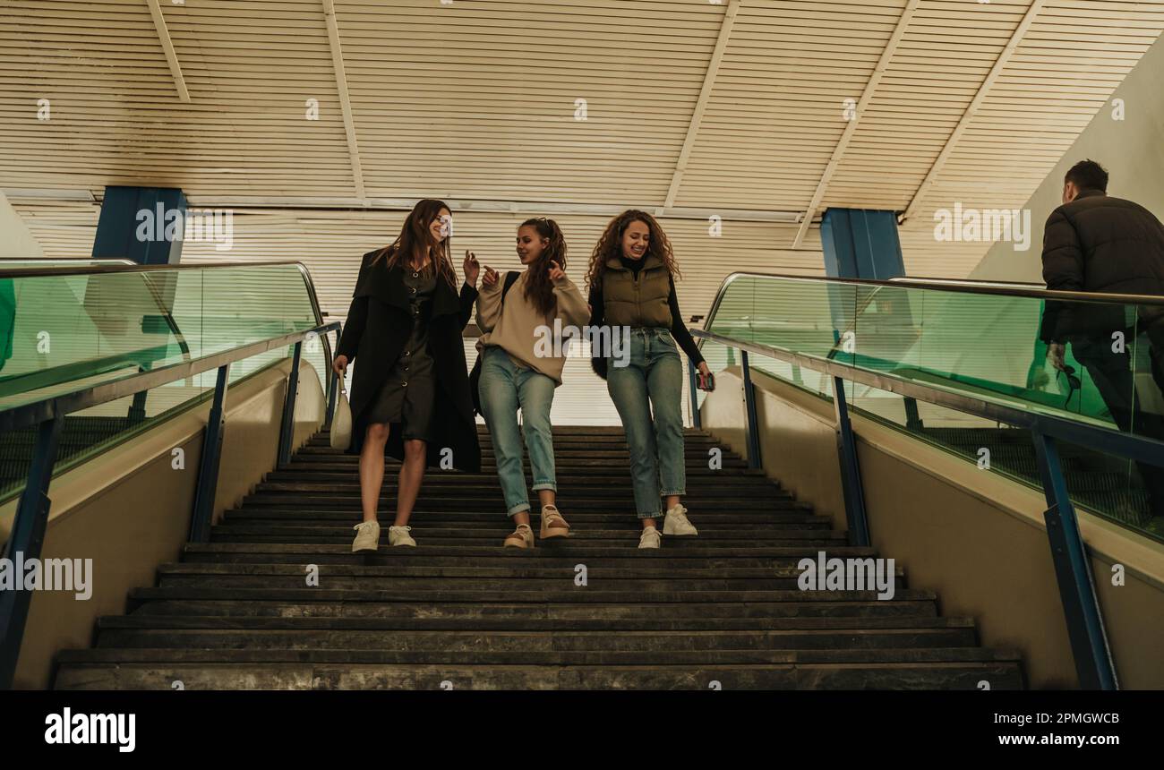 Three girls smiling while having fun conversation. Long haired brunette ...