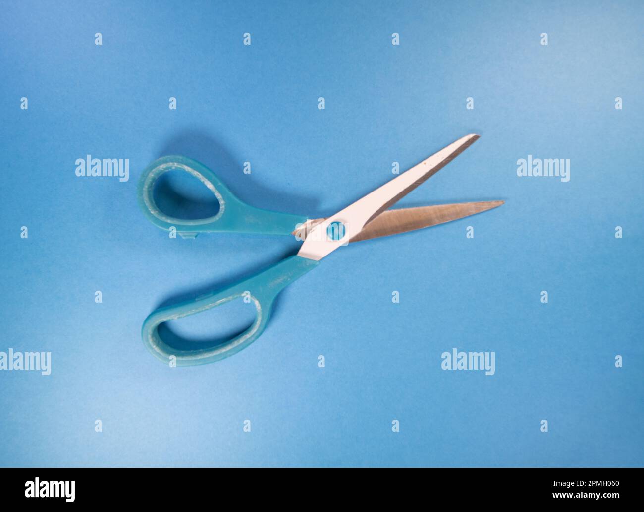 single pair of blue handled scissors half open isolated on a blue ...