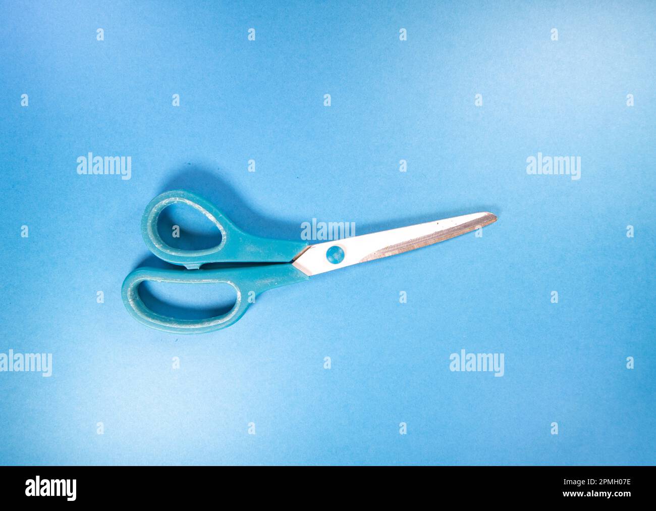 single pair of blue handled scissors isolated on a blue background ...