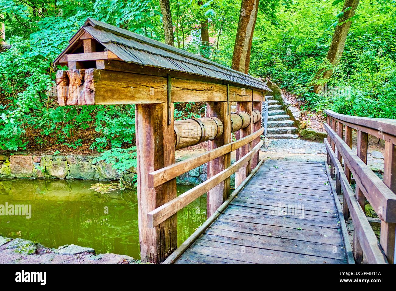 The old wooden footbridge with a dam on small river in Sofiyivsky Park ...
