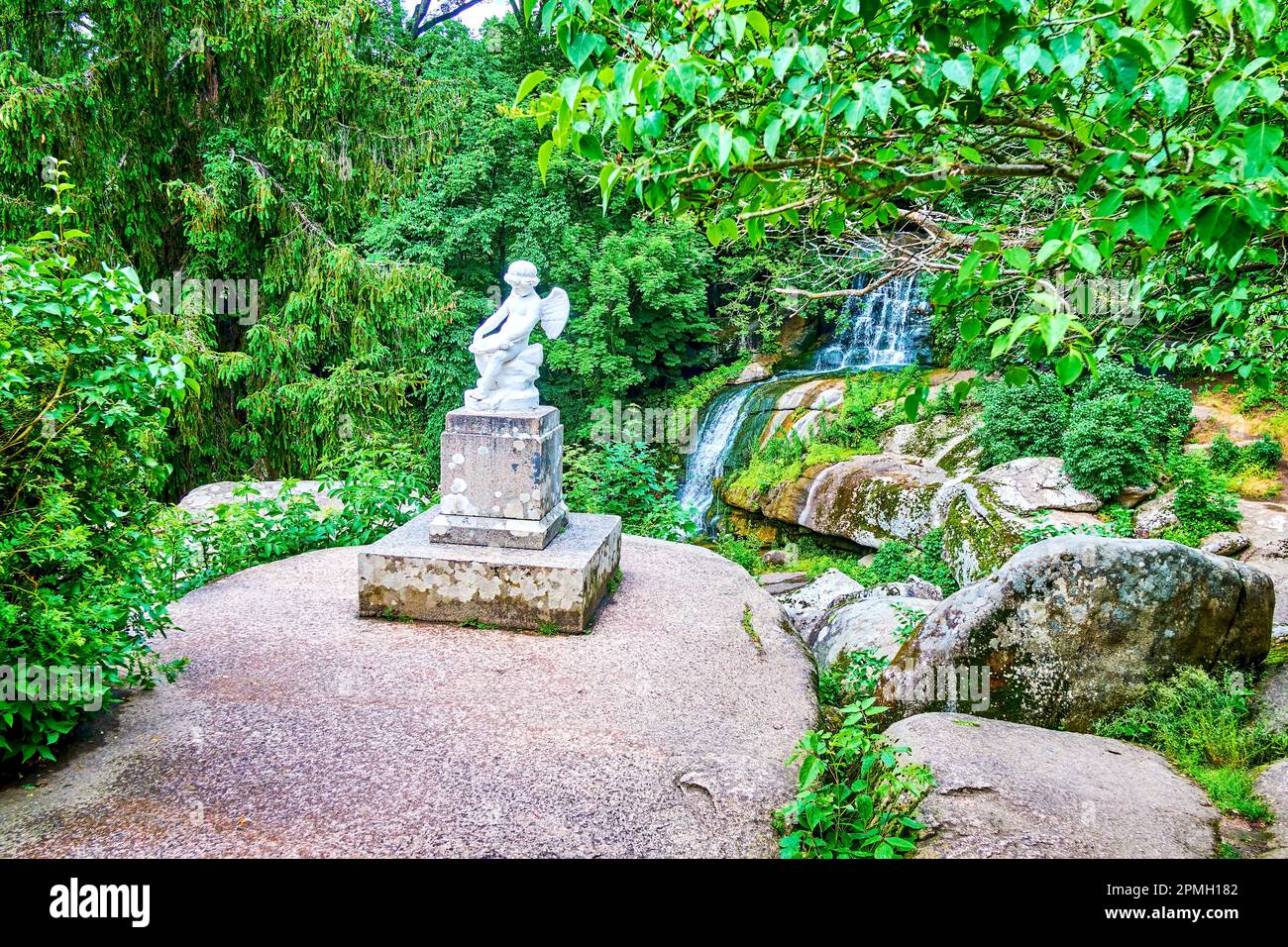The marble statue of the cupid and waterfal on background in Sofiyivka ...