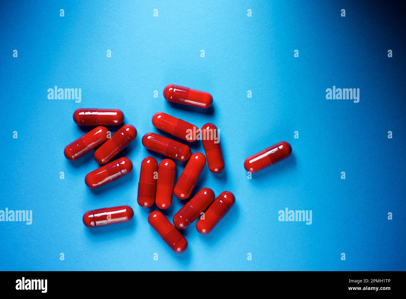 Red medicine capsules on a blue table Stock Photo - Alamy