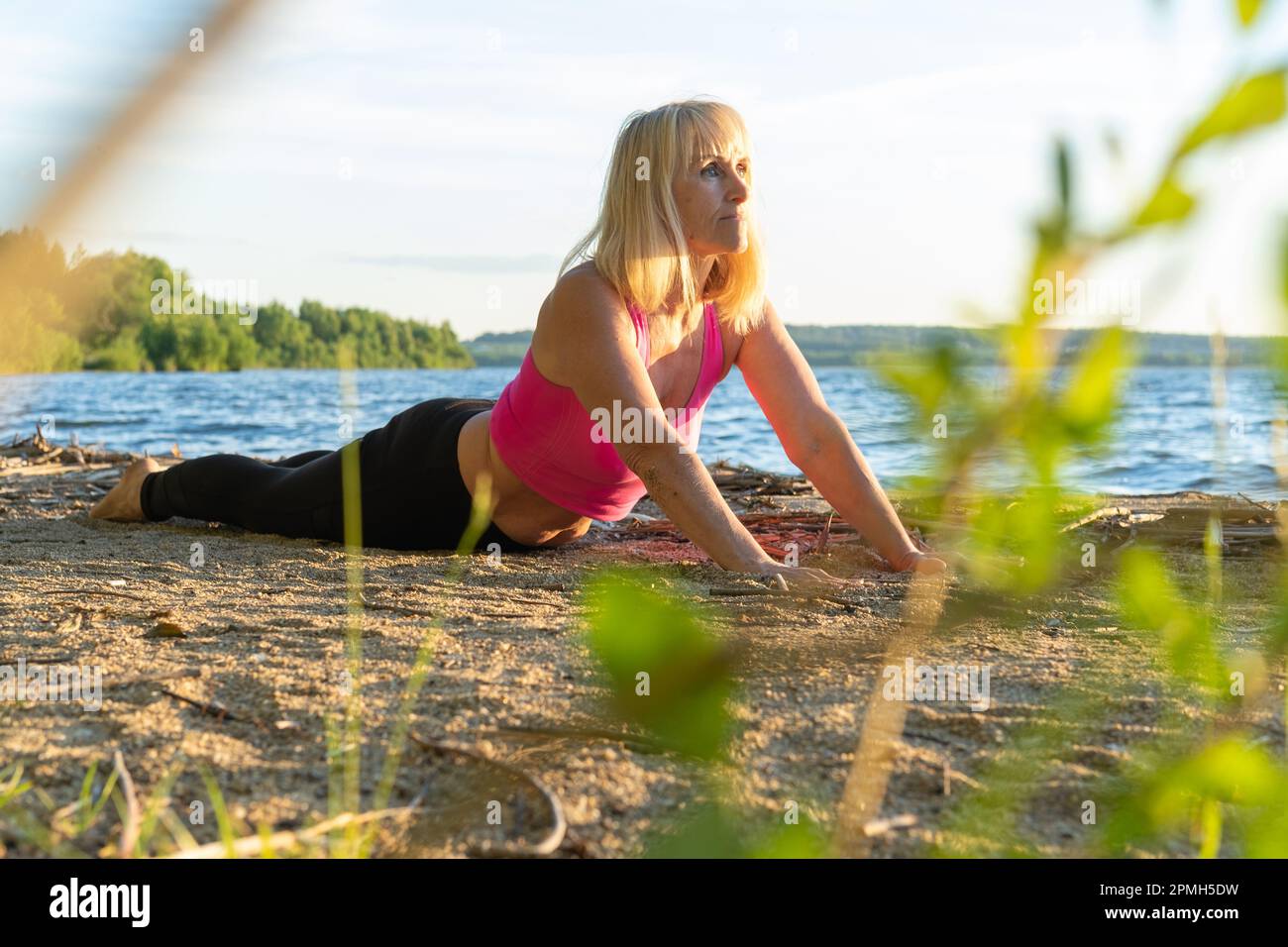 An elderly woman lifting her head up in a snake pose, practicing yoga ...