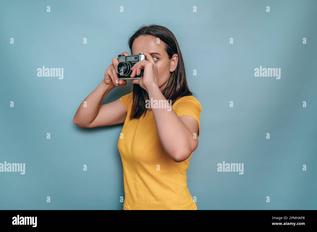 A woman takes pictures with an old film camera. Yellow boot cap, black ...