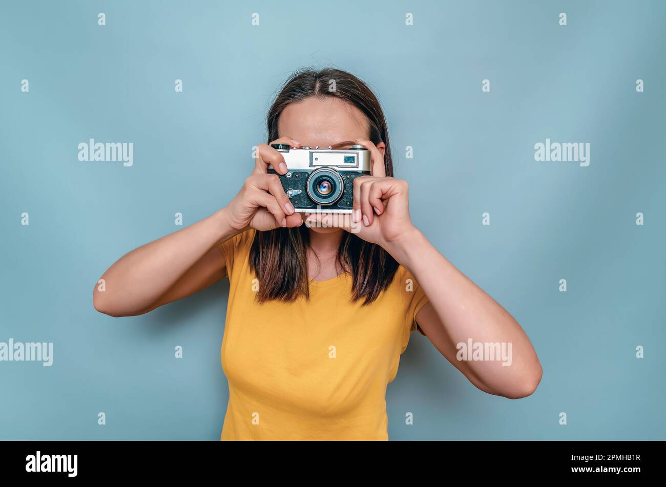 A woman takes pictures with an old film camera. Yellow boot cap, black ...