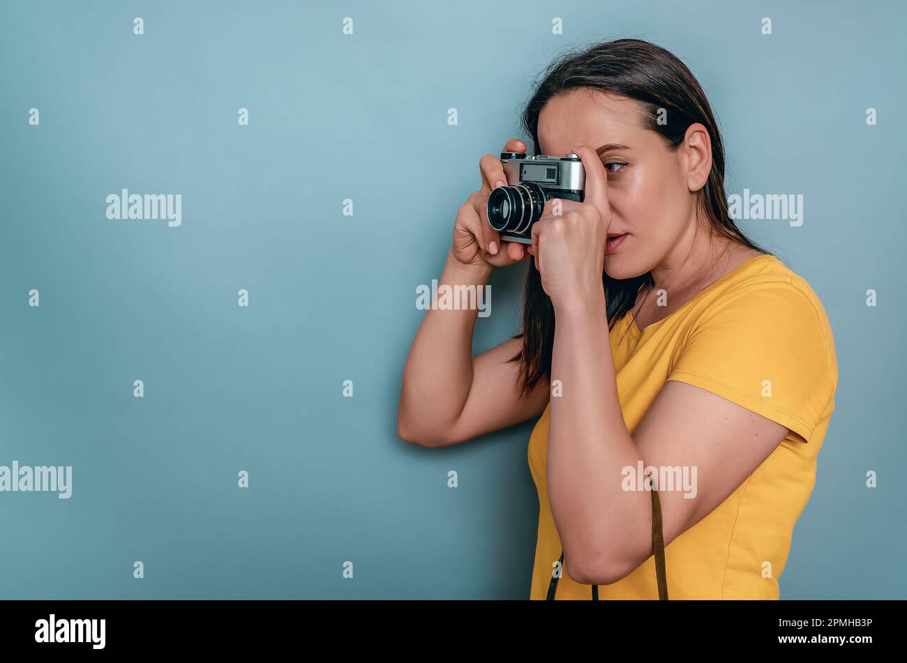 A woman takes pictures with an old film camera. Yellow boot cap, black ...