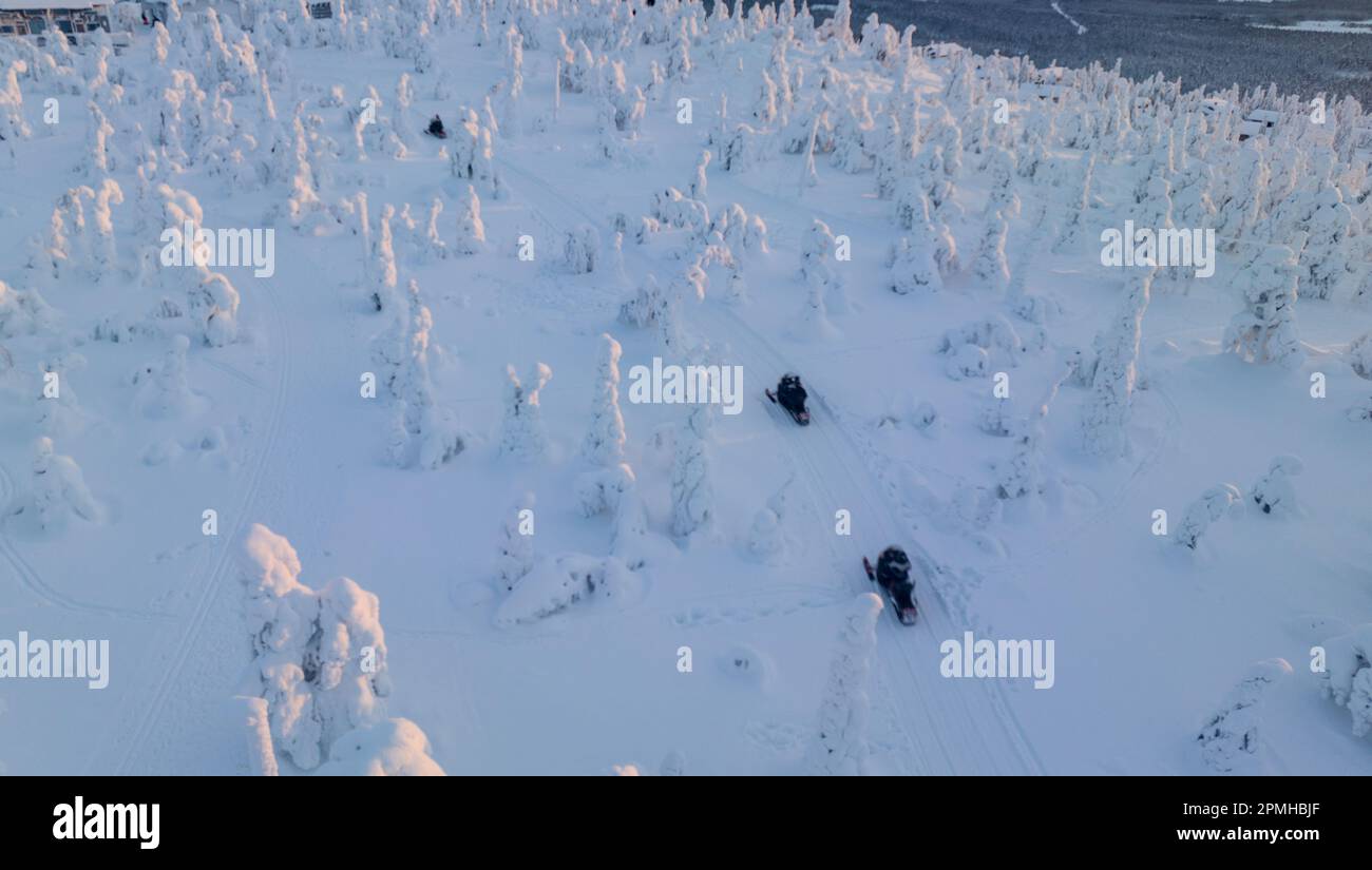 Aerial view of a motor sledge driving uphill a snowy fell, winter dusk ...