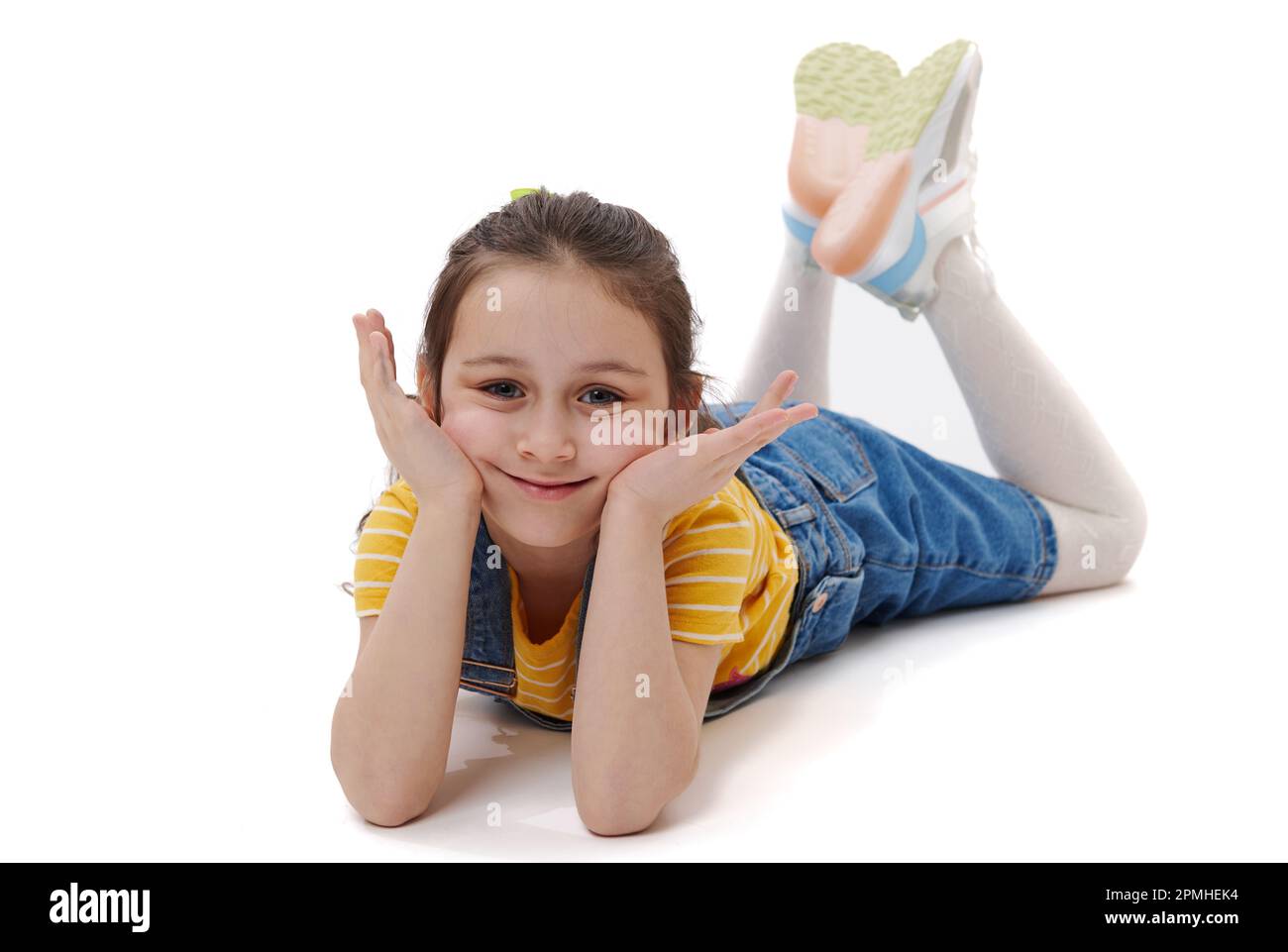 Close-up lovely little child girl lying on her belly on while isolated ...