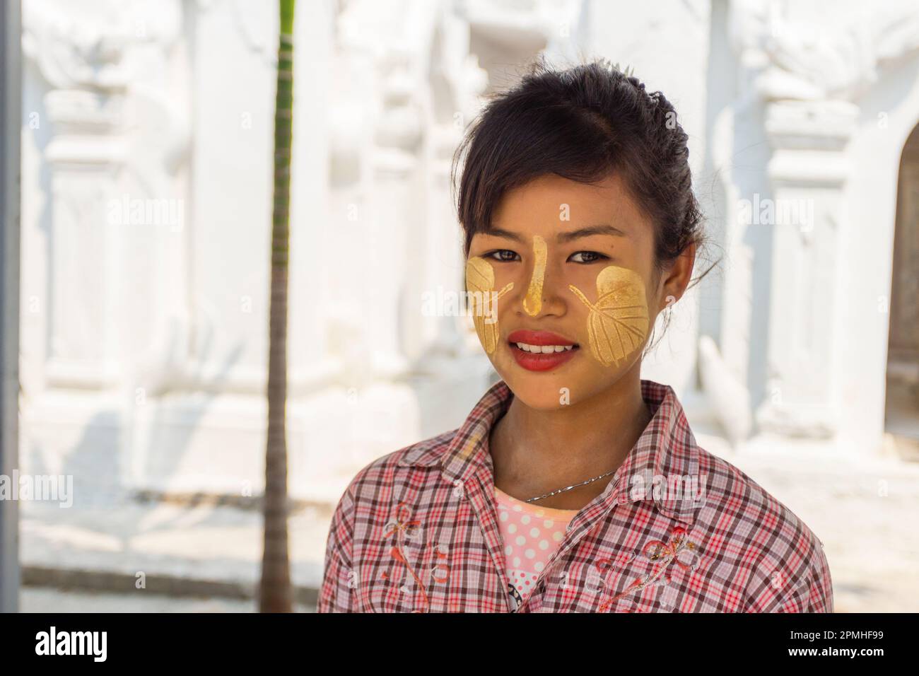 Young Burmese woman with leaves painted on her cheeks with thanaka ...