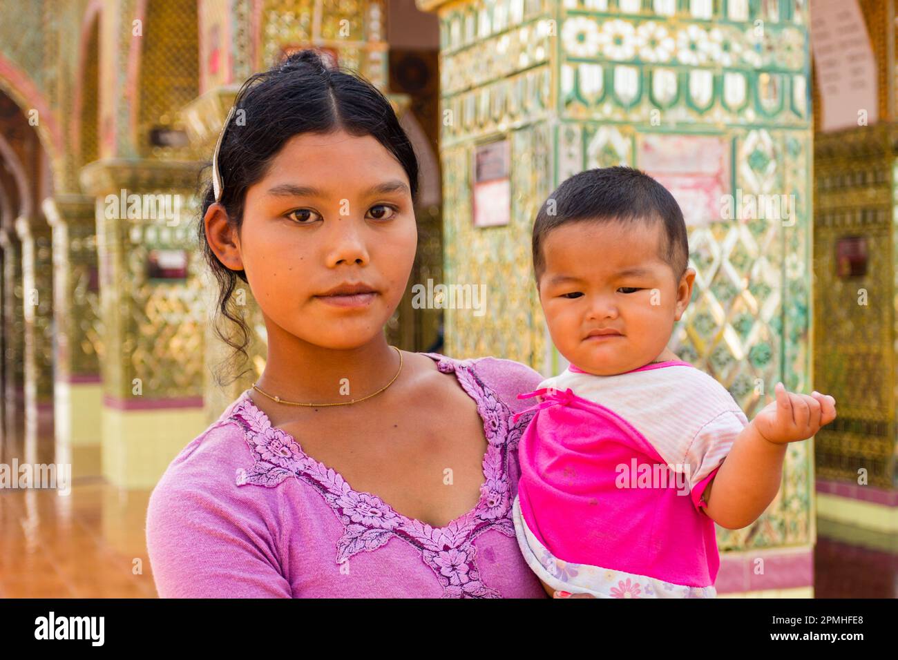 Young Burmese woman holding her small boy and looking at camera ...