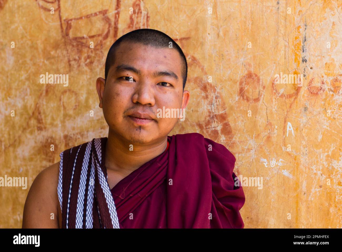 Portrait of monk looking at camera in front of temple, Bagan, Myanmar ...