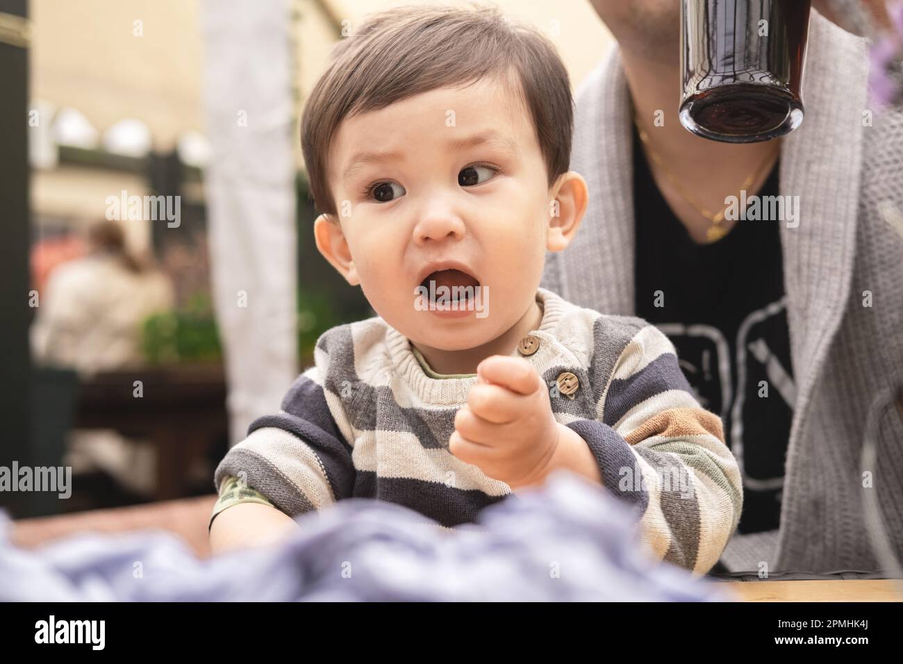 A male infant screaming with big open mouth sitting on his ...