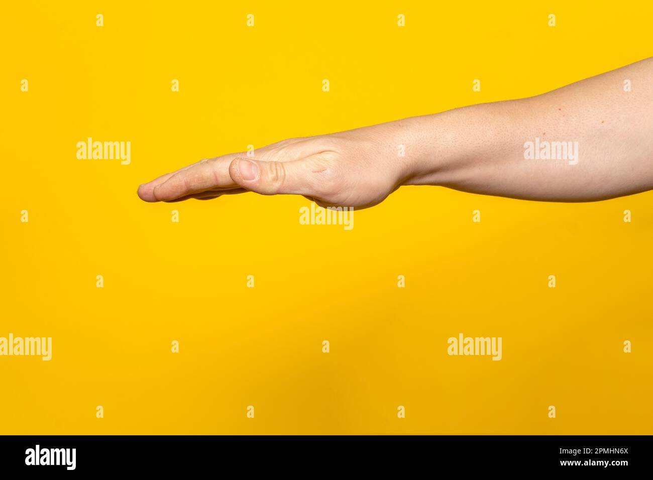 Strong man's arm with palm outstretched upside down isolated on yellow ...