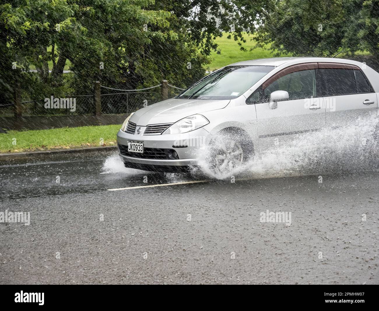 This car is driving through a puddle of water on the street Stock Photo ...