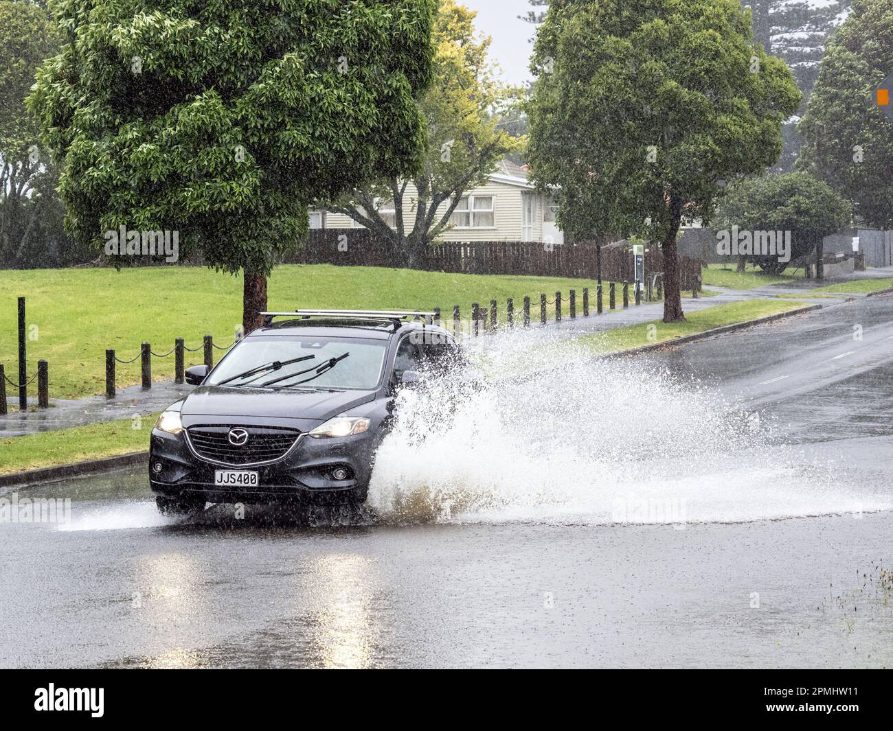 This car is driving through water on a wet road with grass on both ...