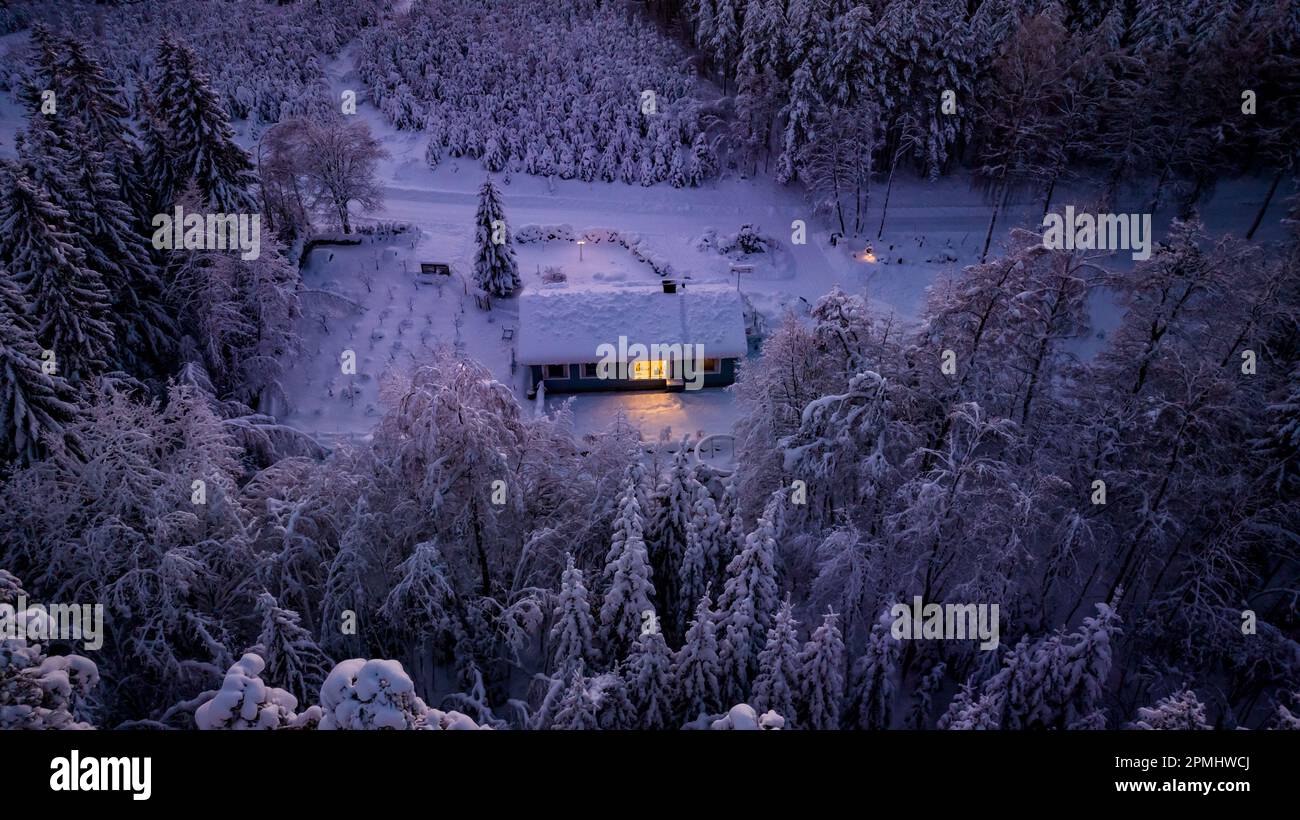 Aerial view around a house with a light on, during a cold winter ...
