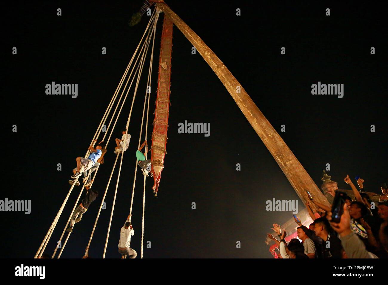 Nepal. 13th Apr, 2023. Devotees climb on a long ceremonial pole called ...