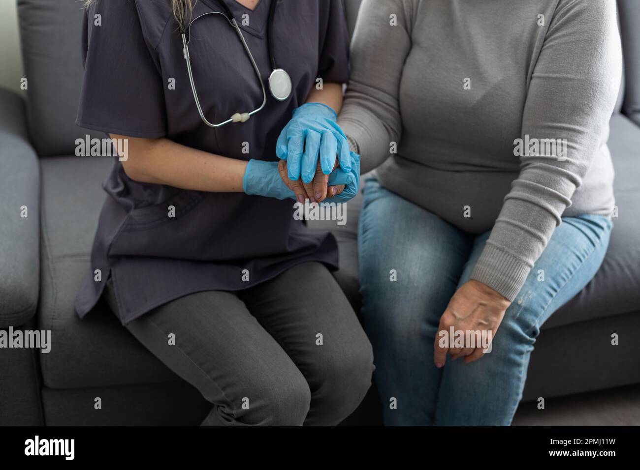 Caring young nurse doctor carer helping holding hands of happy disabled ...
