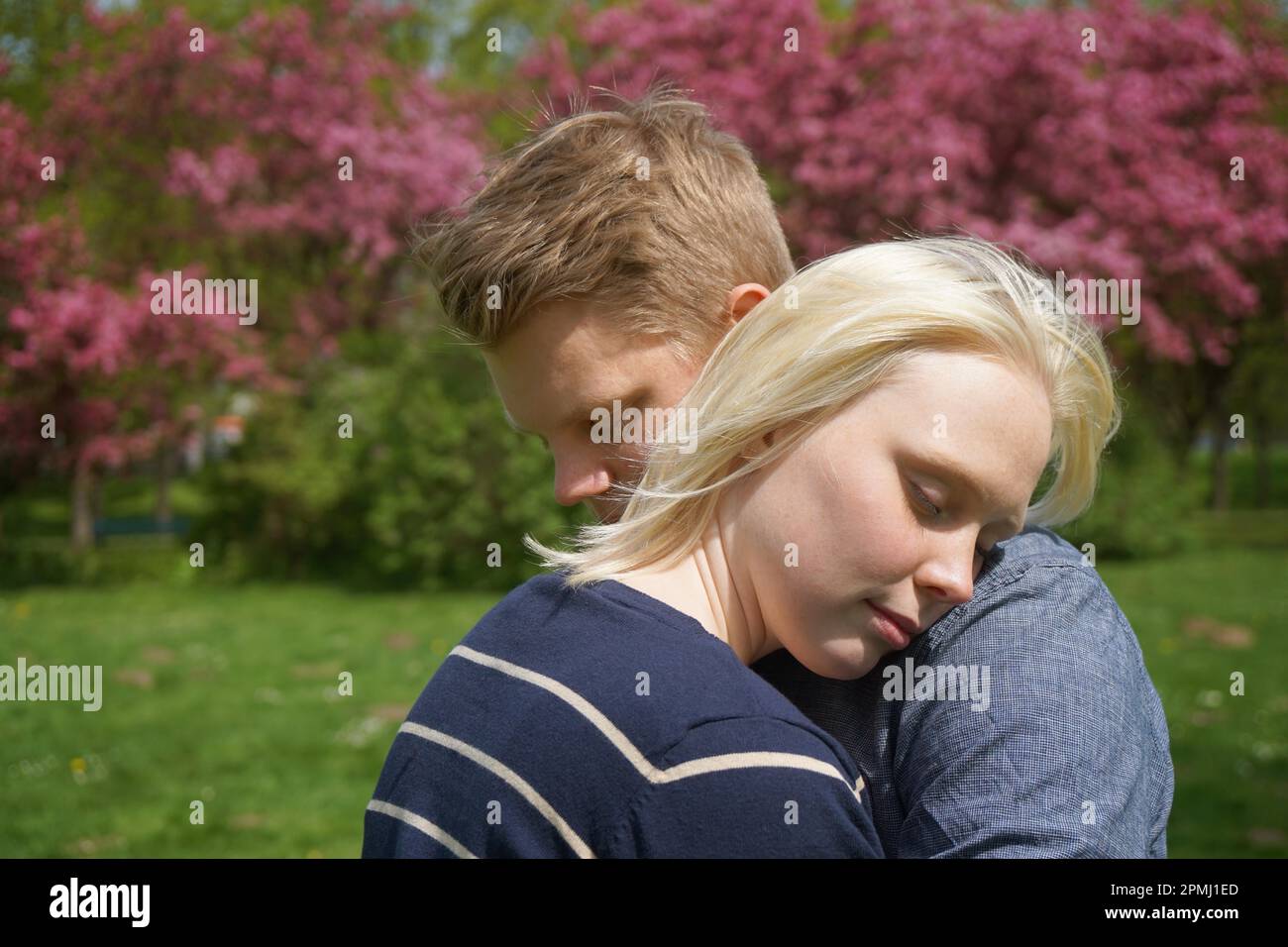 young couple embracing with her head on his shoulder in a park Stock ...