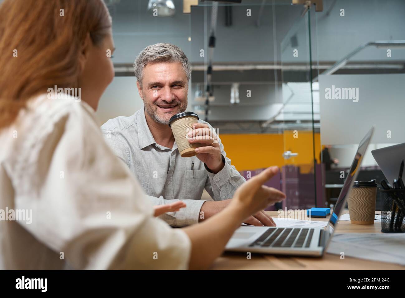 Young woman talking with employee in the office Stock Photo - Alamy