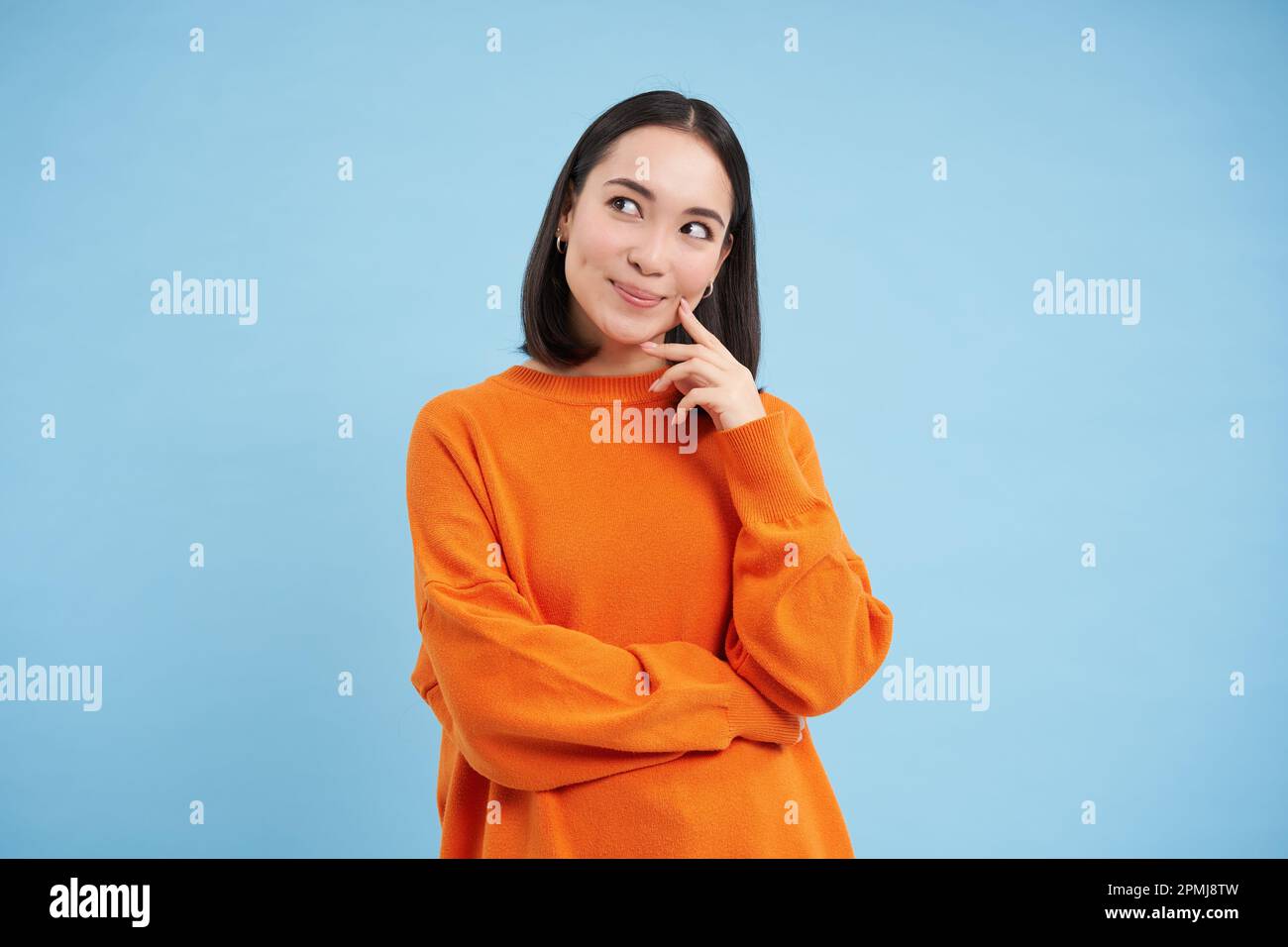 Smiling thinking asian woman, looking up with thoughtful, pleased face ...