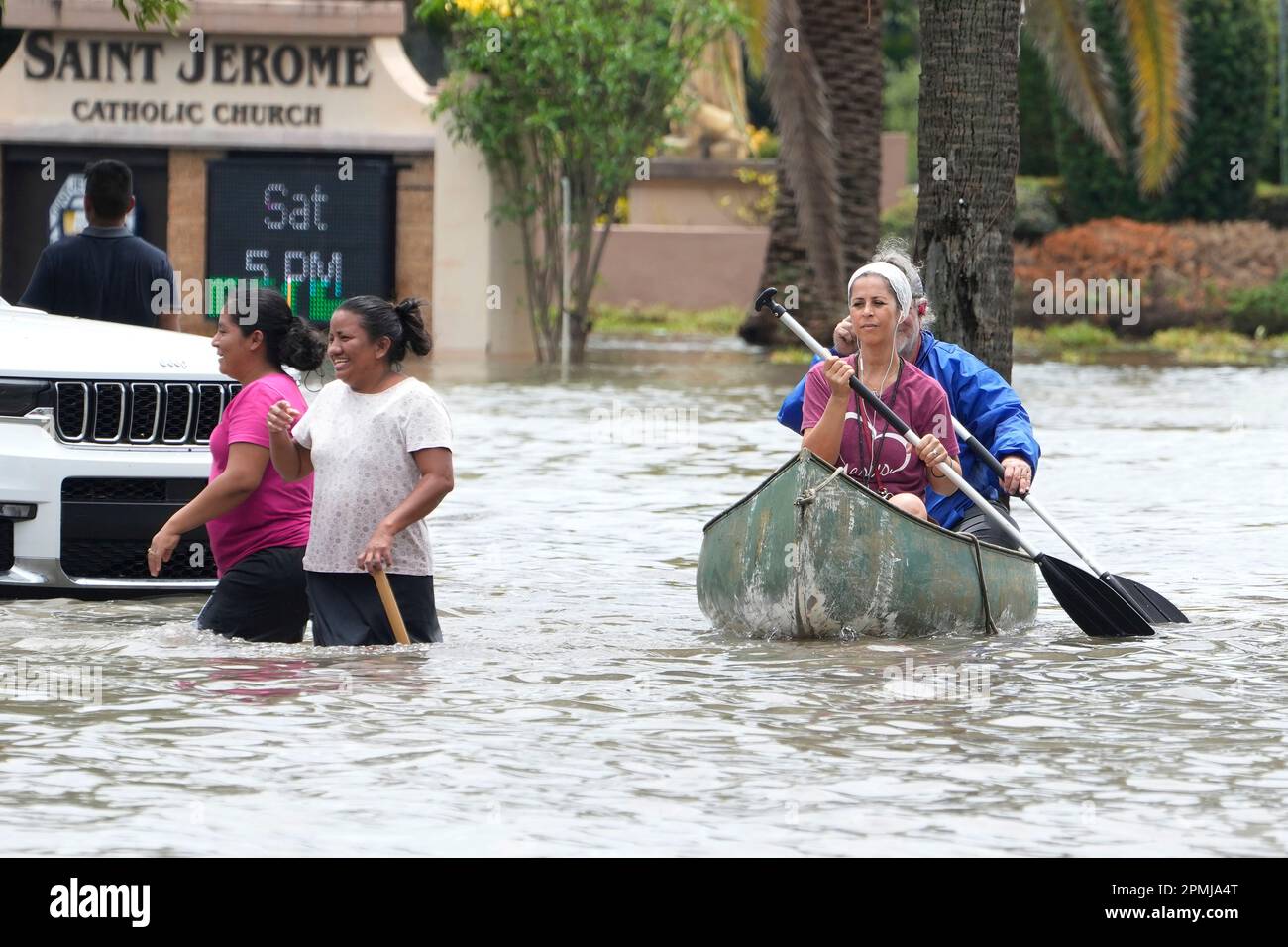 Residents paddle and walk along a flooded road Thursday, April 13, 2023 ...