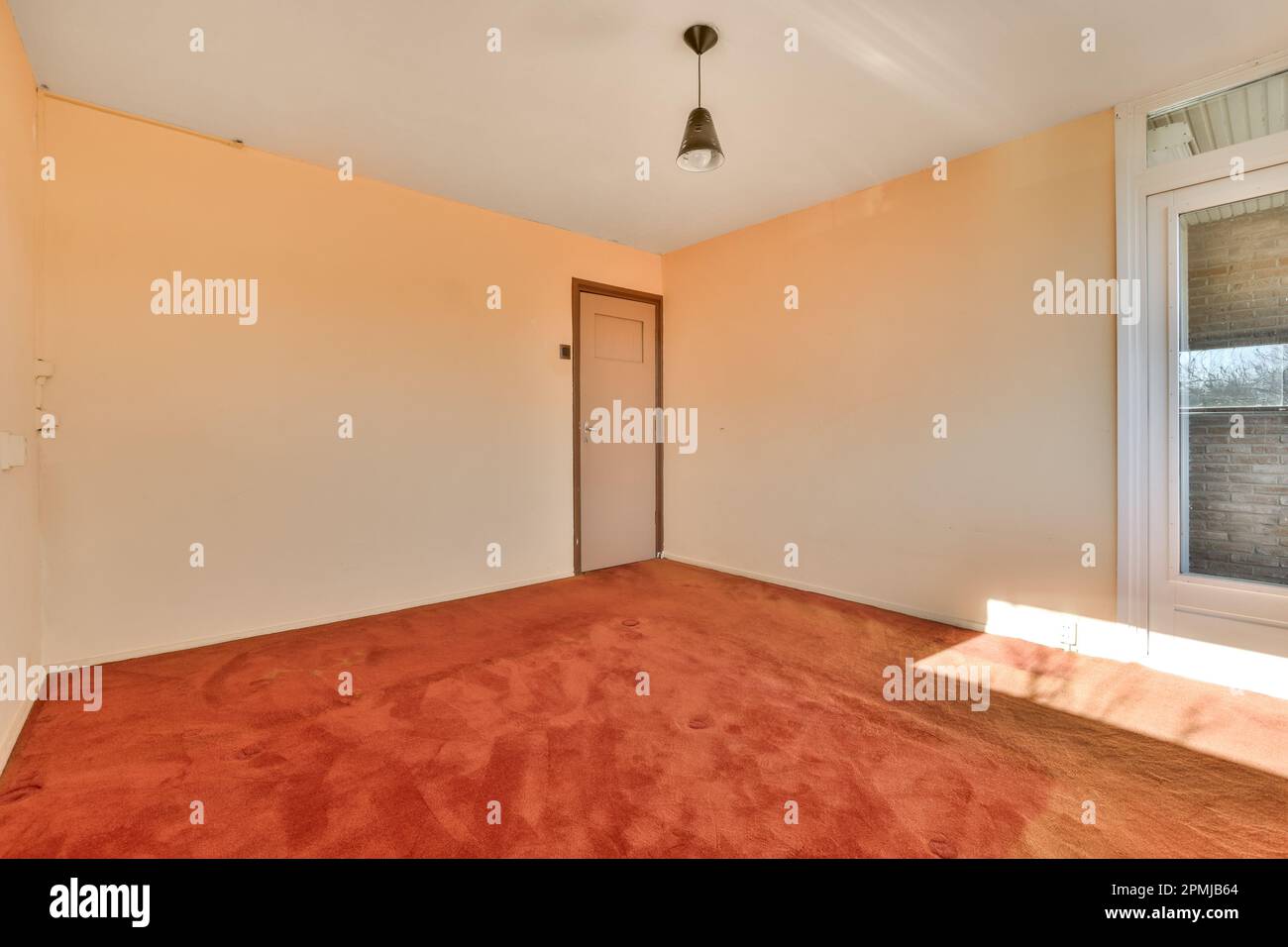 an empty room with red carpet and brick wall in the corner to the left ...