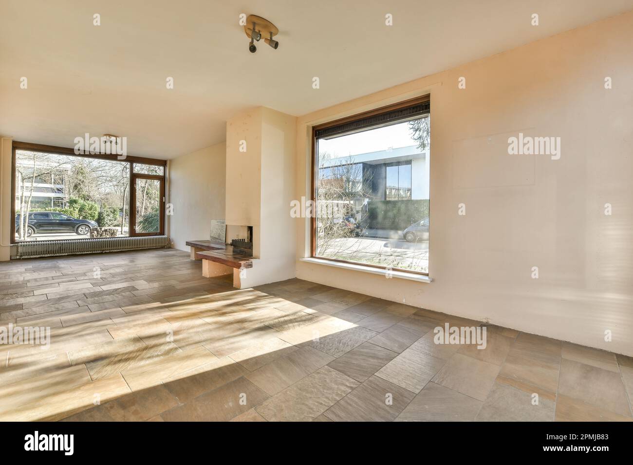 an empty living room with wood flooring and large windows looking out ...