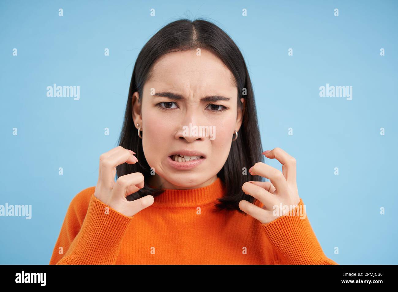 Close up of angry japanese woman, clenches her fists and looks furious ...