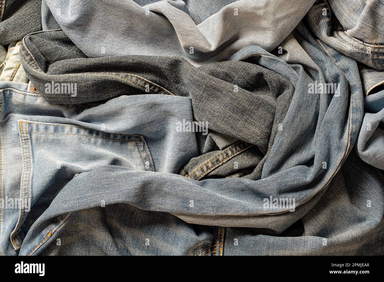 Lots of crumpled jeans pants, close up. Denim background. The concept ...
