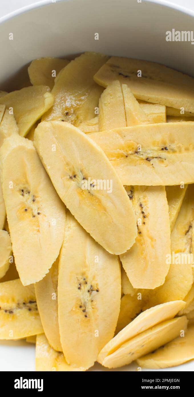 slices of ripe plantains in a white bowl, slices of yellow plantains ...