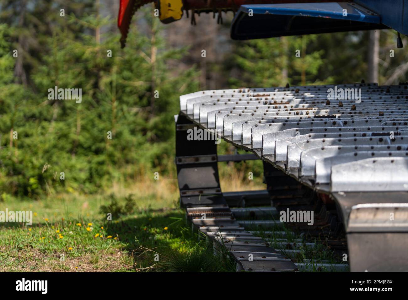 Metal caterpillars of a snowplow in a warehouse on a summer site on a ...