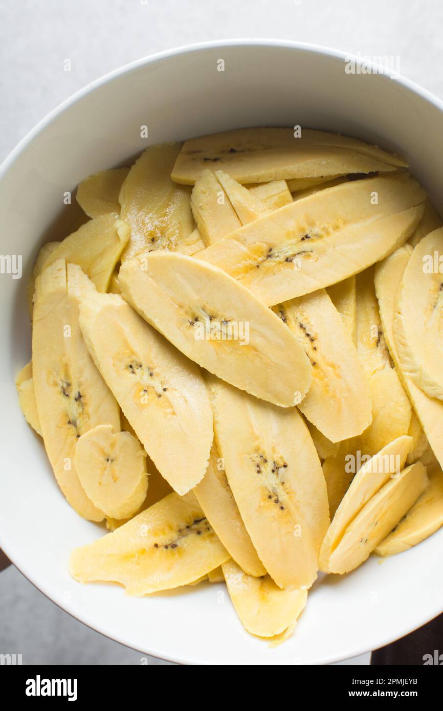 slices of ripe plantains in a white bowl, slices of yellow plantains ...