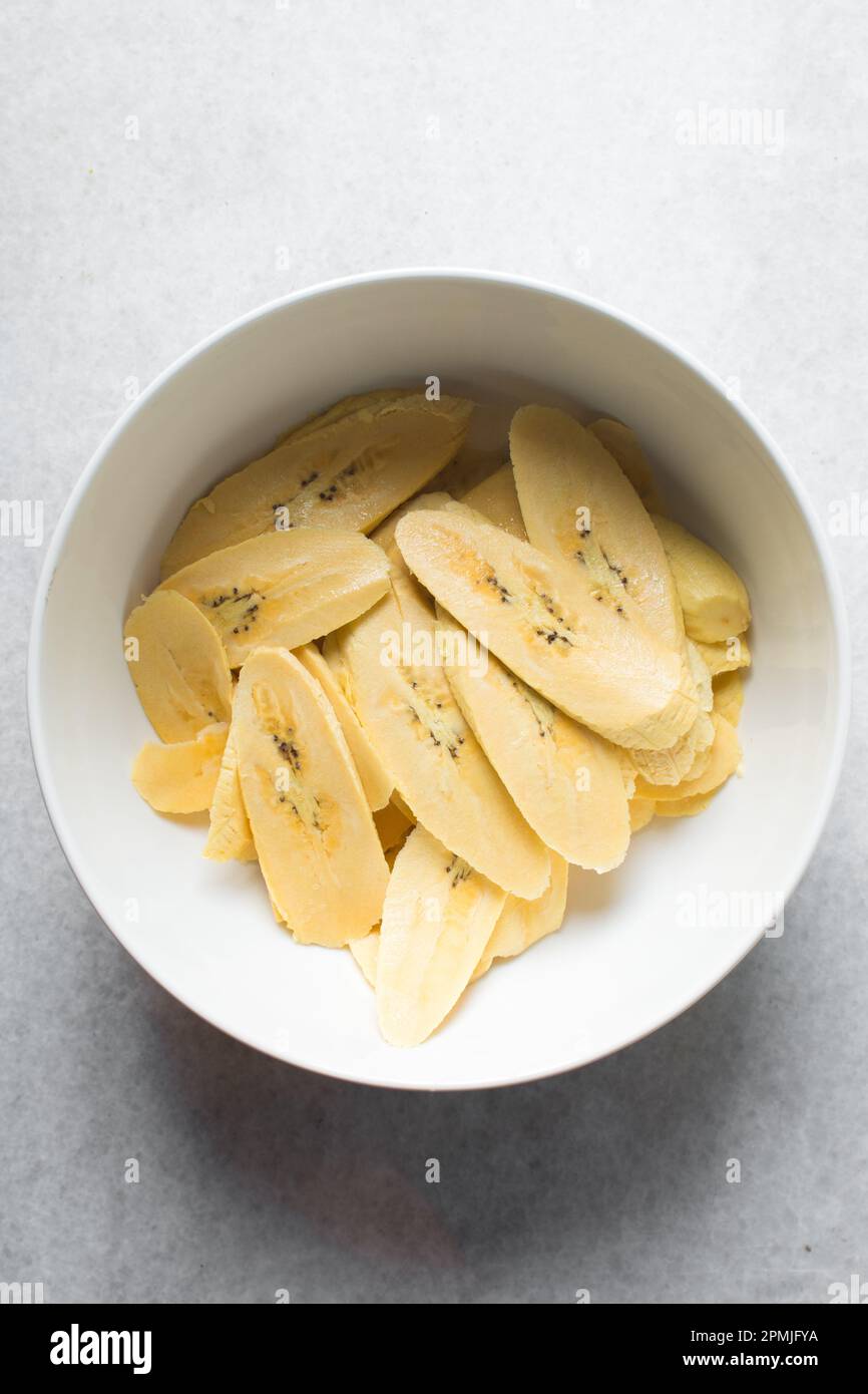 slices of ripe plantains in a white bowl, slices of yellow plantains ...