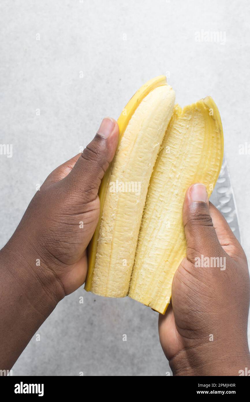 Hands peeling ripe plantains, yellow plantains for frying being peeled ...