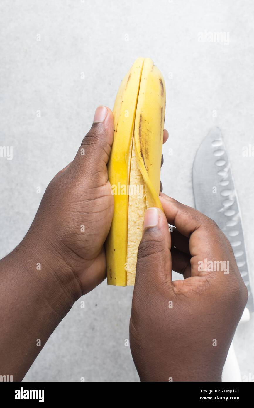 Hands peeling ripe plantains, yellow plantains for frying being peeled ...