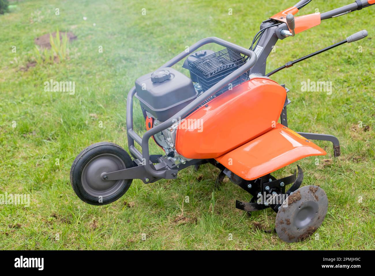 A man works the land in the garden with a cultivator, prepares the soil ...