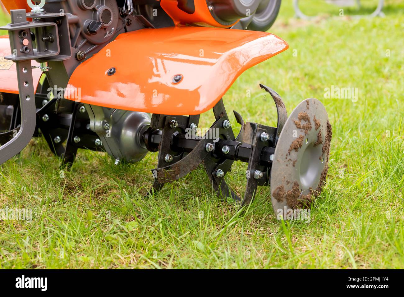 A man works the land in the garden with a cultivator, prepares the soil ...
