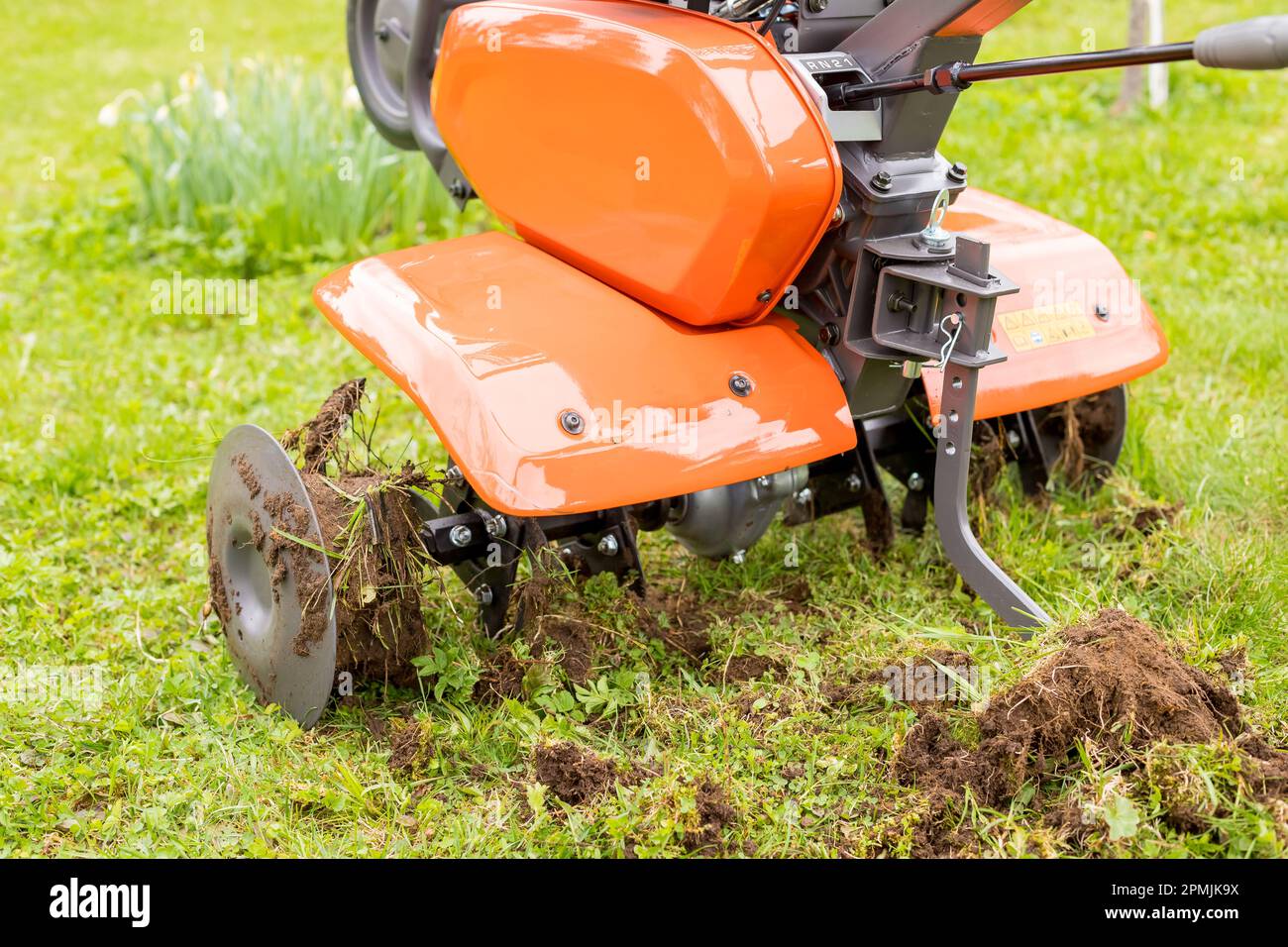 A man works the land in the garden with a cultivator, prepares the soil ...
